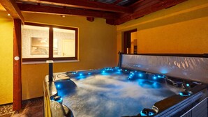 Uma banheira de hidromassagem com luzes LED azuis, teto de madeira e uma janela com vista para o exterior.