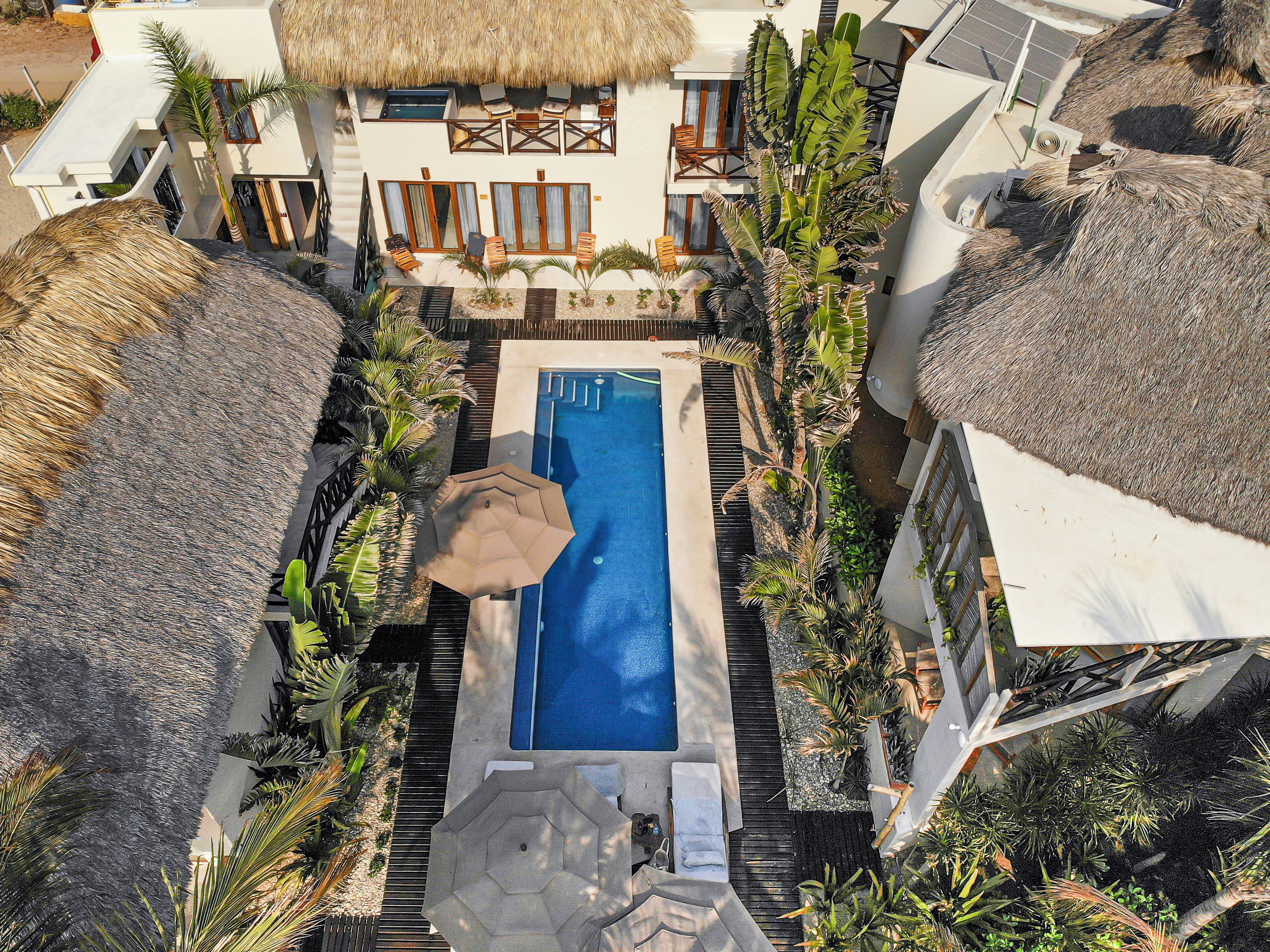 Resort com piscina, construções de telhado de palha e área de estar ao ar livre.