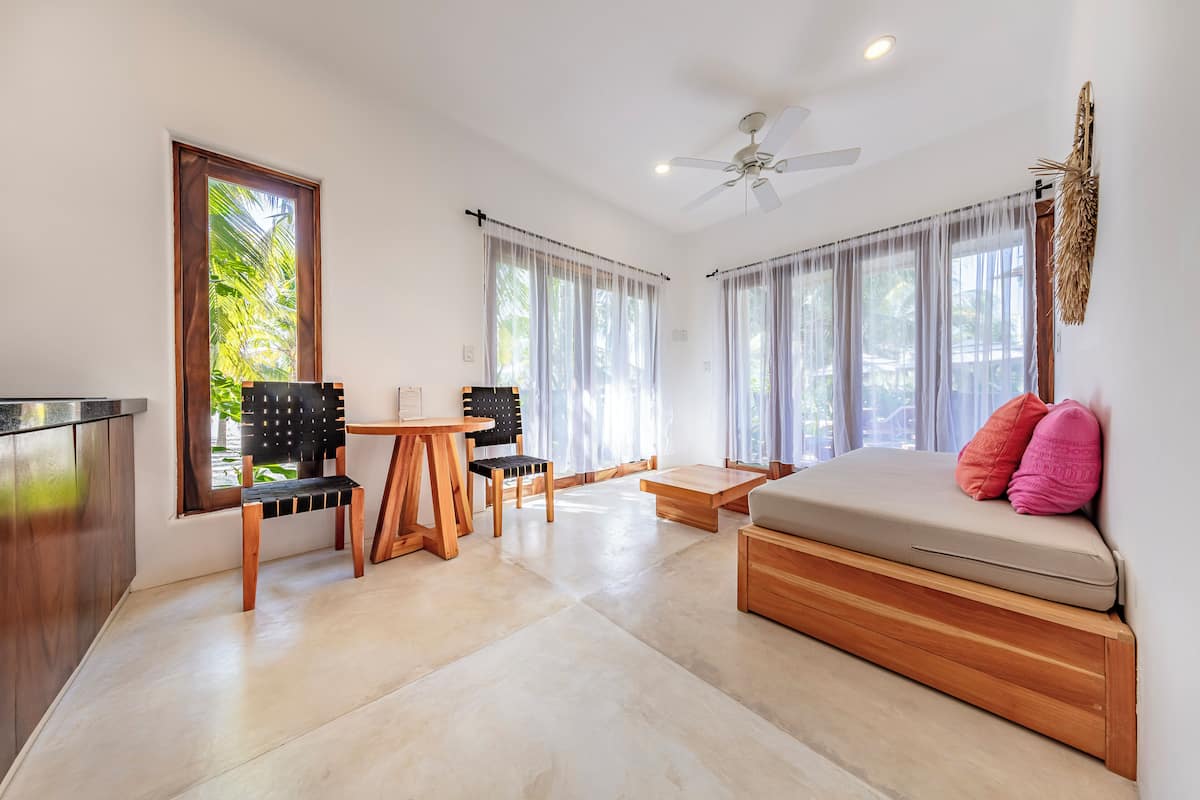 Quarto moderno com cama, escrivaninha, cadeira e uma pequena mesa.