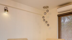 Sala de estar com sofá bege, mesa de centro de madeira, luminária de cristal e aparelho de ar condicionado.