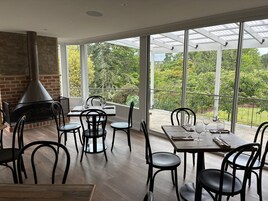 Uma sala de jantar com lareira de tijolos, janelas amplas e vista para o exterior.