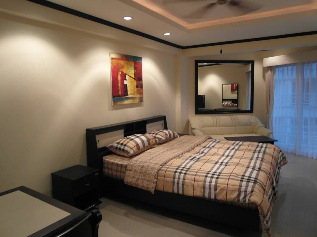 Quarto com cama, mesa de cabeceira, ventoinha no teto, quadro, espelho e janela com cortinas.
