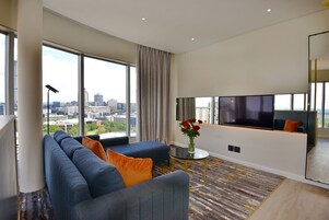 Uma sala de estar moderna com um sofá grande, uma mesa de centro e uma televisão.