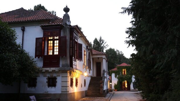 Um edifício tradicional com telhado em cerâmica, escadaria que leva à entrada e um caminho de cascalho.