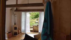 Um quarto rústico com teto de madeira, uma lareira pequena, uma janela com cortinas e uma toalha pendurada.