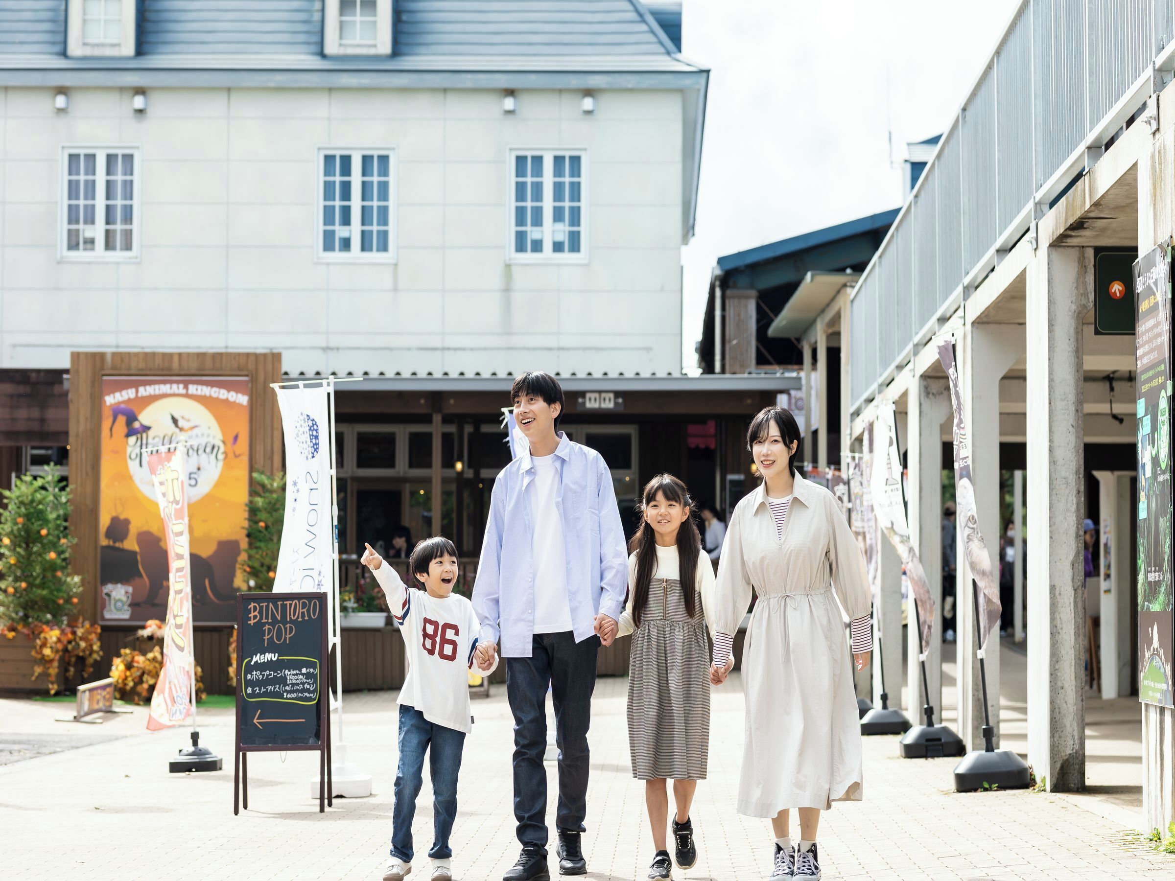 Uma família caminhando pela calçada, com um edifício ao fundo.
