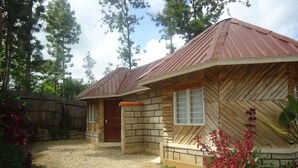 Uma casa rústica de madeira com telhado de chapa de metal, entrada de tijolo e janela com moldura branca.