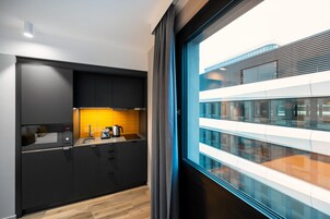 Cozinha moderna com forno embutido, cafeteira e janela com vista para um edifício.