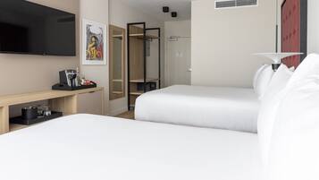 Quarto de hotel com cama, escrivaninha, televisão e guarda-roupa.