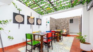 Uma área de refeições com mesa e cadeiras, um jardim no teto e uma parede de pedra.