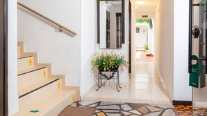 Corredor de hotel com escadas, um espelho, um arranjo de flores e uma área de recepção.
