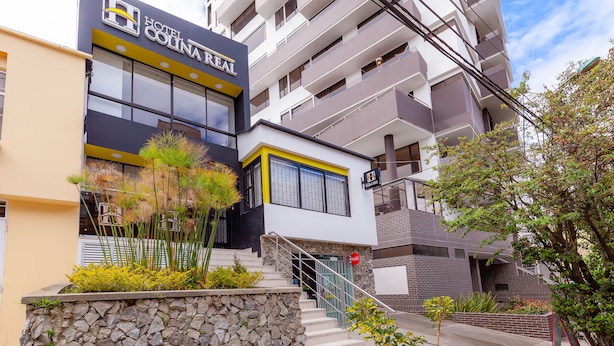 Um hotel com fachada moderna, uma parede de pedra e uma escadaria que leva à entrada.