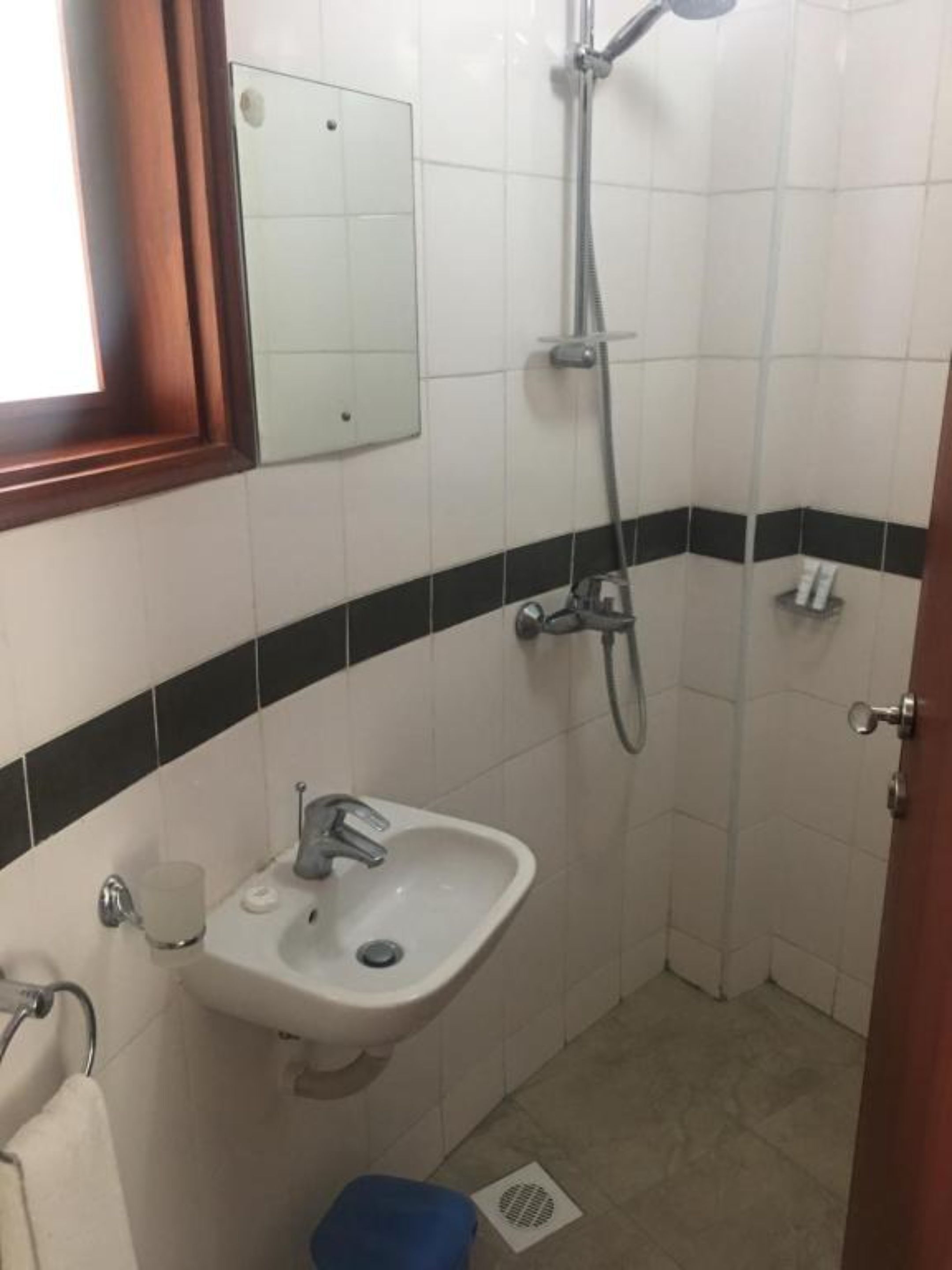 Uma casa de banho pequena com lavatório, espelho, chuveiro e sanita.