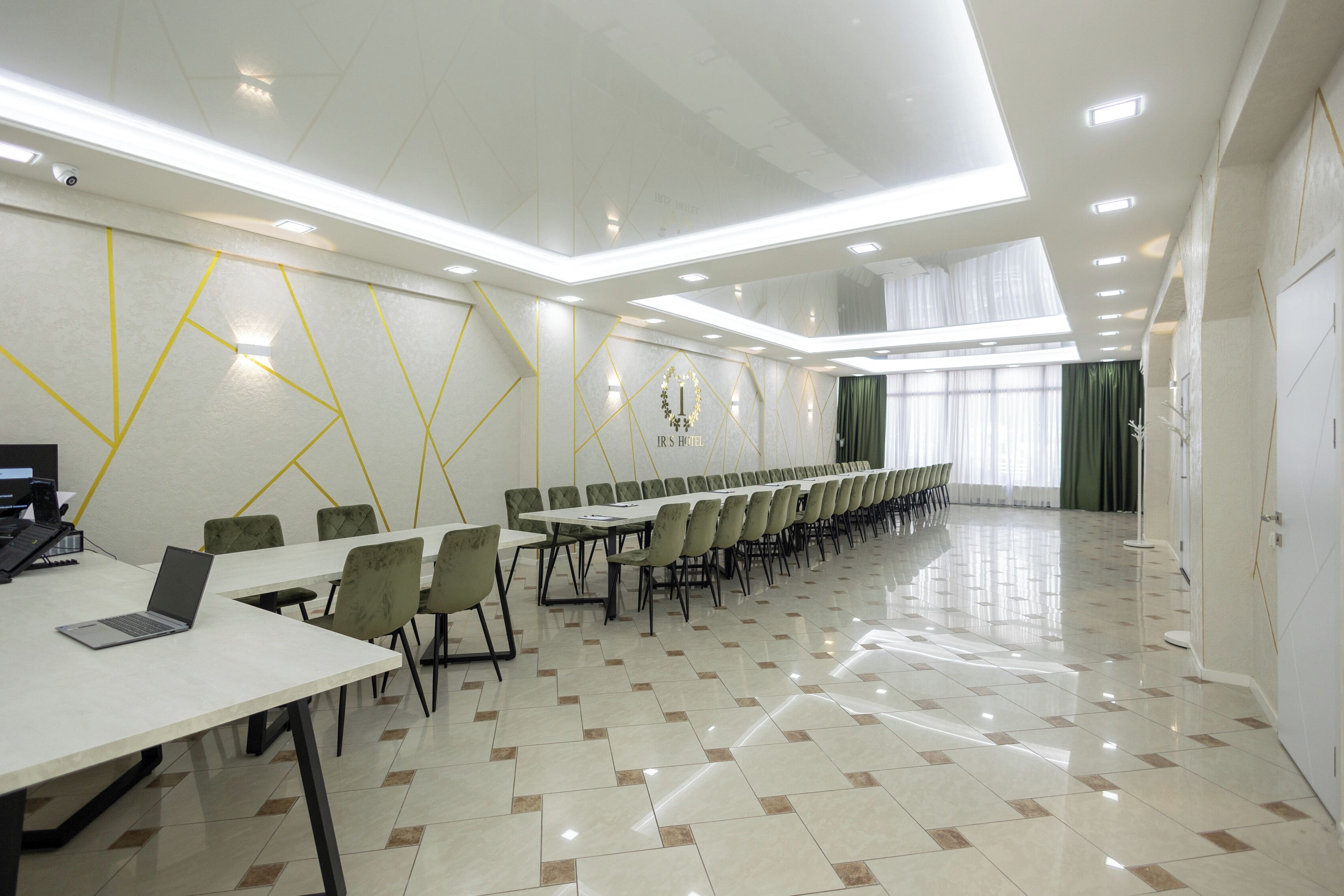 Uma sala de conferência com uma mesa grande, cadeiras e um laptop sobre a mesa.