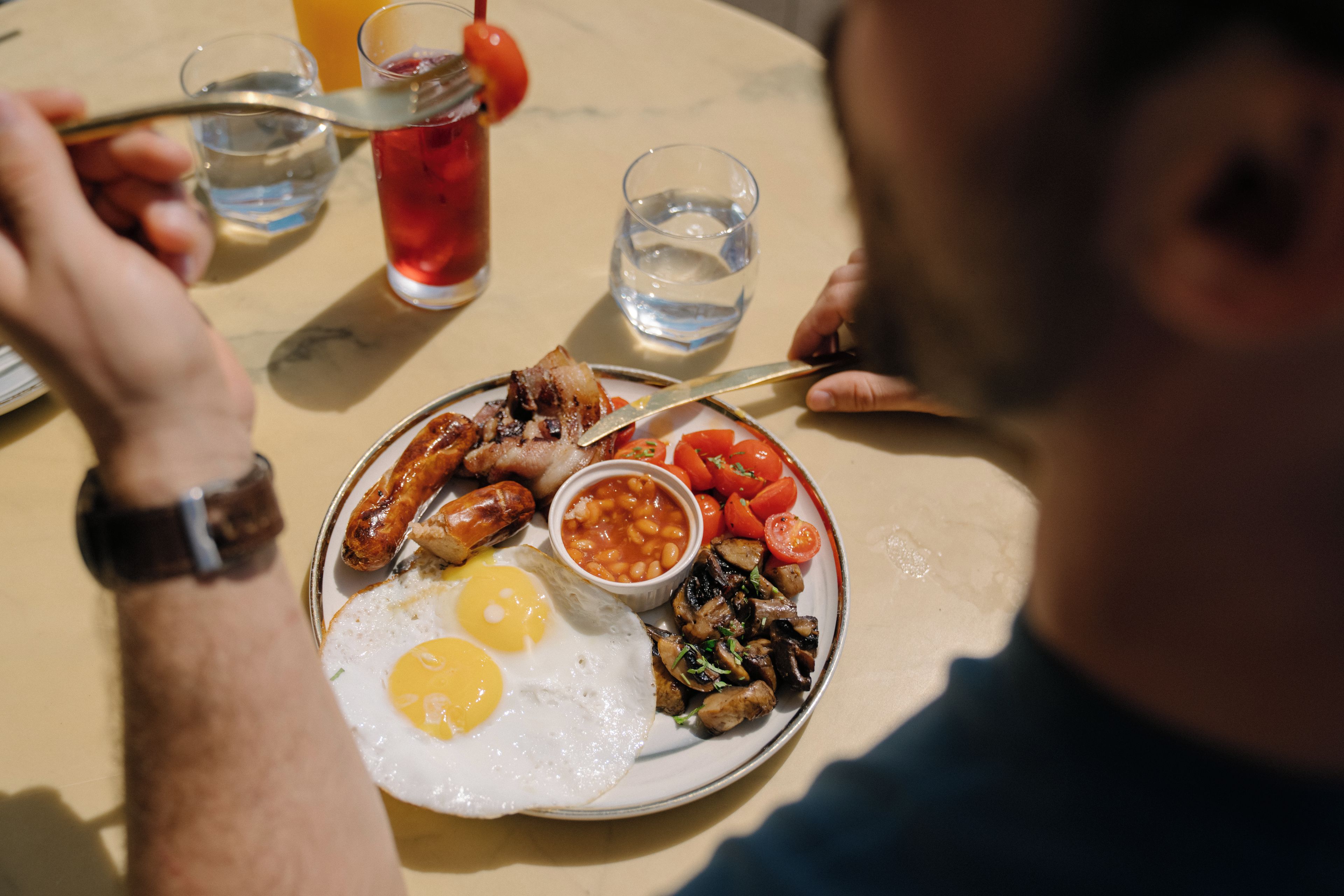 Prato de café da manhã com ovos, linguiça, cogumelos e tomates.