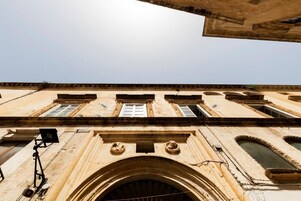 Fachada de um edifício histórico com janelas em arco e uma entrada central.
