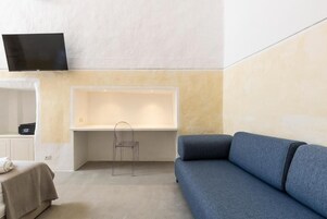 Uma sala de estar moderna com um sofá azul, uma poltrona transparente e uma banheira embutida.