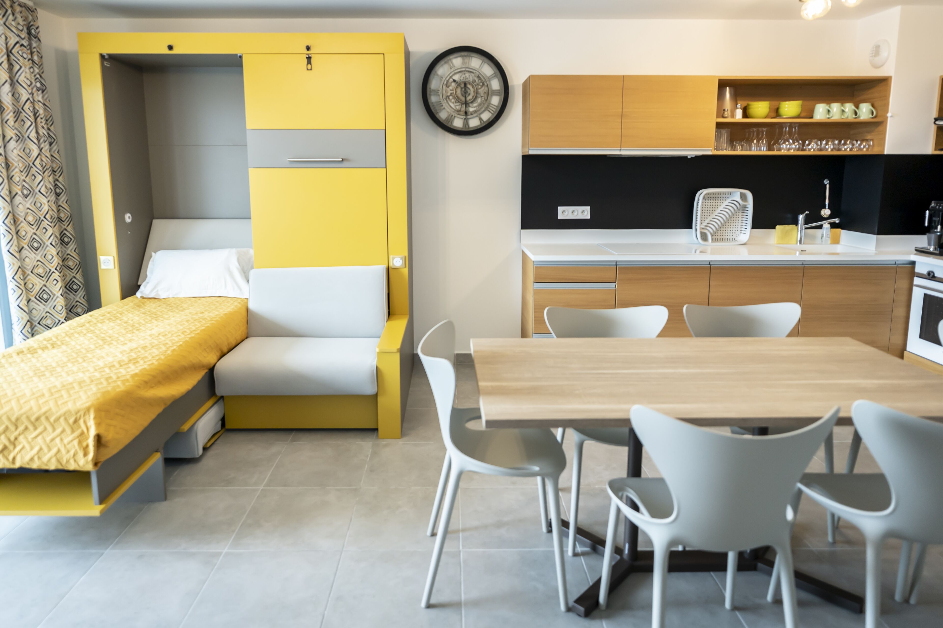 Um espaço compacto com cama, mesa de jantar e cozinha compacta.