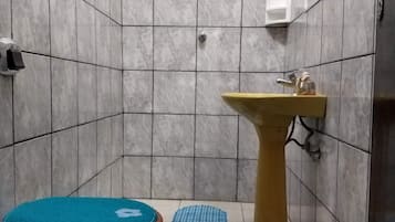 Uma casa de banho pequena com sanita, lavatório e chuveiro.