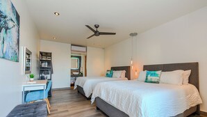 Quarto moderno com duas camas, uma escrivaninha e um banco.