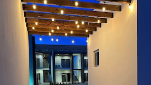 Um edifício moderno com galeria coberta, área de estar ao ar livre e ampla vista do interior através de grandes janelas.