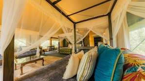 Um quarto com tenda, com uma cama, uma mesa e um sofá.