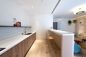 Uma cozinha moderna com bancada branca, armários de madeira e um espaço bar com banquetas.