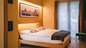 Cama bem arrumada com cabeceira, um quadro emoldurado acima e uma janela com cortinas.