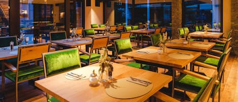 Um restaurante com várias mesas e cadeiras, cada conjunto completo com talheres e guardanapos.