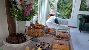 Mesa de buffet com diversos alimentos e um arranjo decorativo de orquídeas.