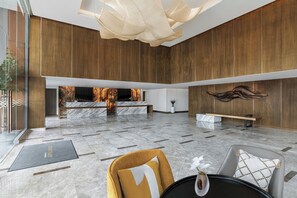 Um hall amplo com piso de mármore, um balcão de recepção e uma área de estar com lareira.