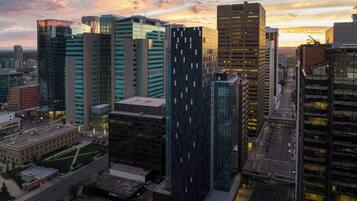 Paisagem urbana com edifícios modernos altos, um estacionamento e céu claro ao entardecer.