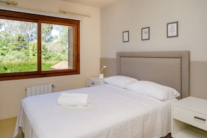 Um quarto com uma cama, uma mesa de cabeceira, persianas e um radiador.
