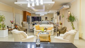 Ampla sala de estar com sofá, mesa de centro e diversas luminárias pendentes.
