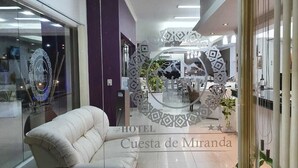 Um saguão de hotel com uma área de estar central, um sofá e uma parede decorativa.