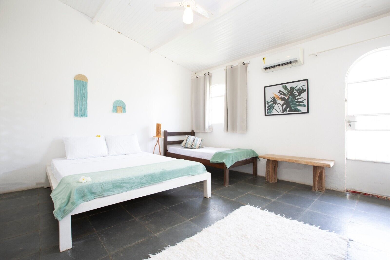 Um quarto com uma cama, um banco, uma mesinha e um quadro na parede.