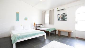 Um quarto com uma cama, um banco, uma mesinha e um quadro na parede.