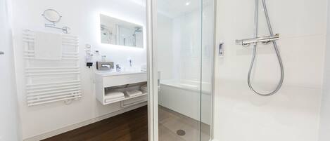 Casa de banho moderna com cabine de duche em vidro, lavatório embutido e toucador com espelho e porta-toalhas.