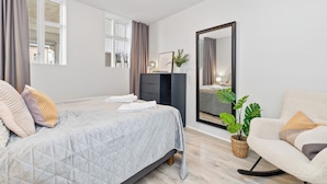 Quarto moderno com cama, penteadeira, espelho e um vaso de planta.