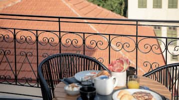 Uma varanda com uma mesa posta para o café da manhã, incluindo ovos, croissants e uma xícara de café.