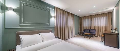 Quarto de hotel com uma cama grande, uma escrivaninha, uma cadeira e um sofá.