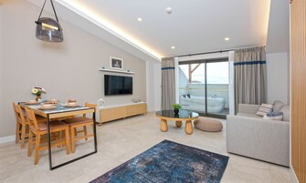 Uma sala de estar moderna com área de jantar, sofá, televisão e vista para uma varanda com hidromassagem.