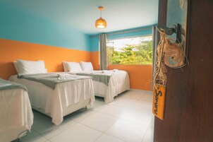 Quarto de hotel com duas camas, janela com vista para vegetação e um enfeite pendurado.