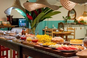 Buffet com diversos alimentos e área de refeições com cadeiras e mesa.
