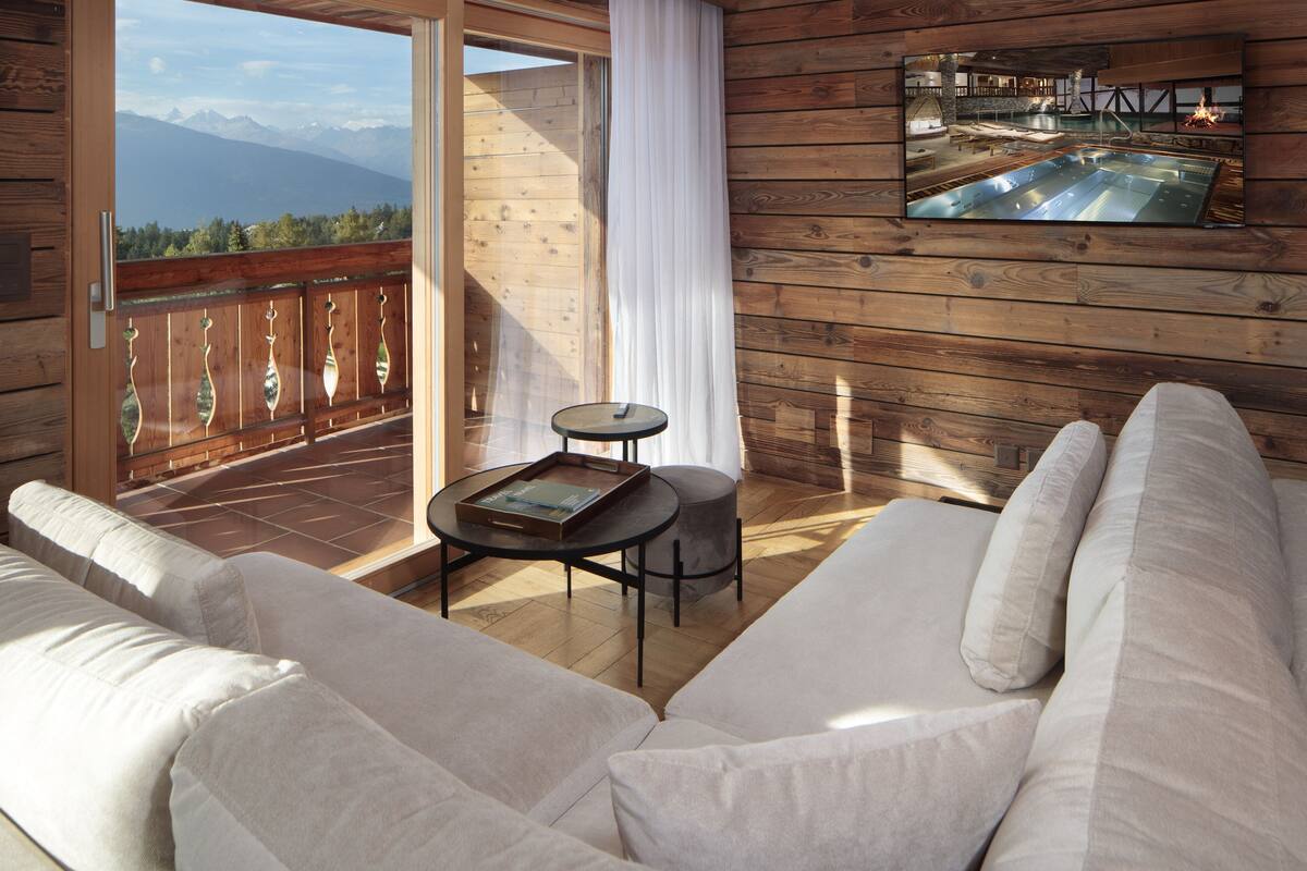 Interior em madeira com varanda, um sofá, uma pequena mesa com bandeja e um quadro na parede.