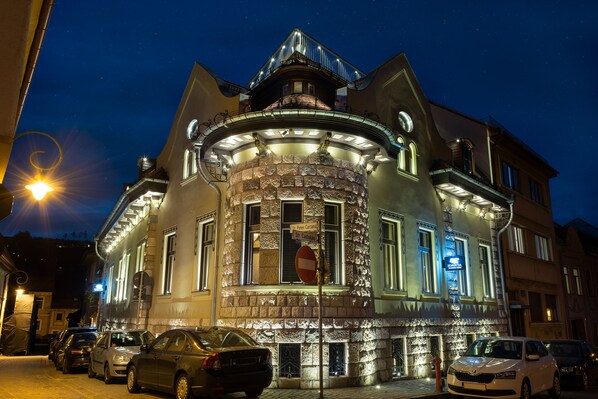 Um edifício histórico com fachada de pedra, varanda com grades e uma placa indicando um restaurante.
