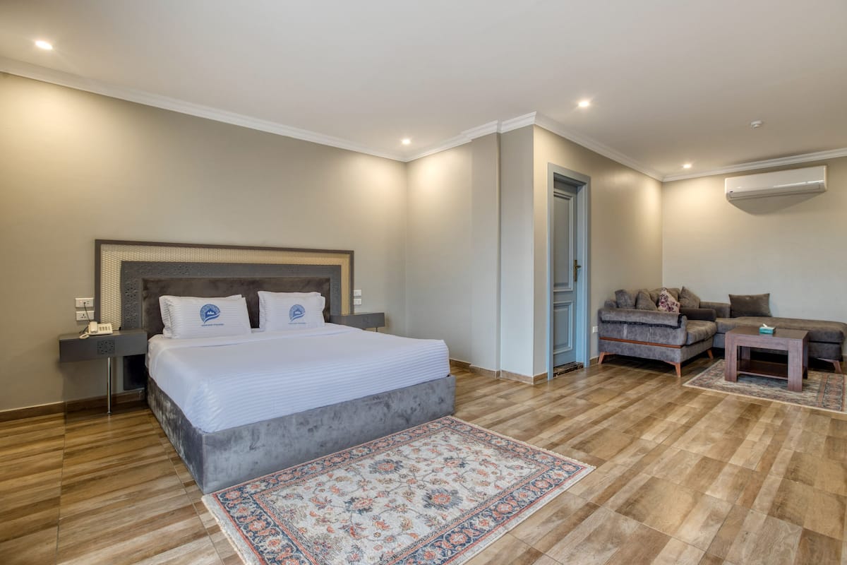 Quarto moderno com uma cama grande, um sofá e uma pequena mesa.