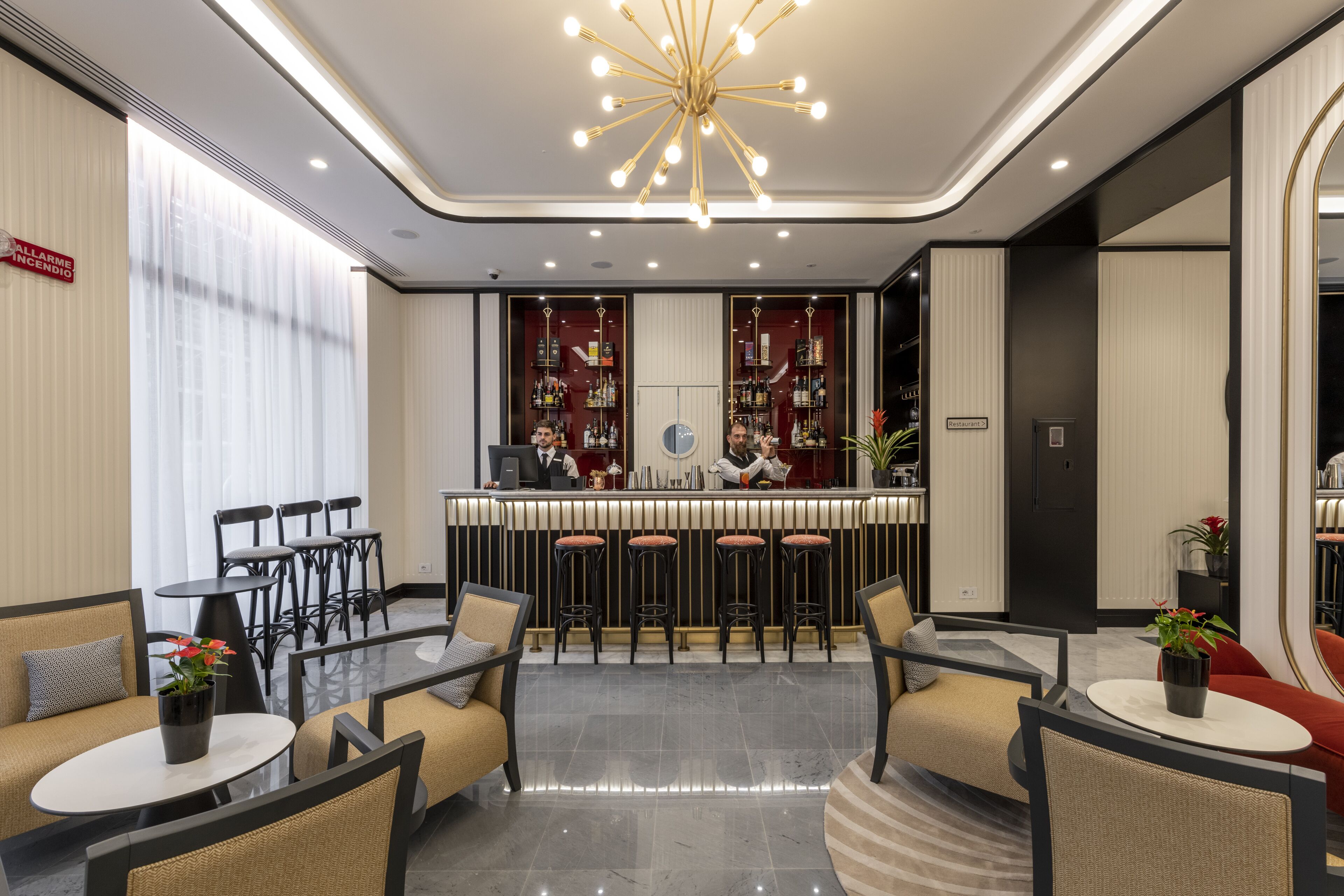Uma área de bar moderna, com balcão, banquetas e um bartender.