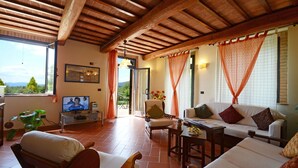 Uma sala de estar aconchegante com televisão, assentos confortáveis e vista para o exterior.