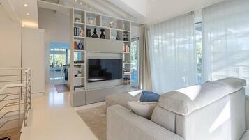 Uma sala de estar moderna com TV embutida, um sofá e uma estante.